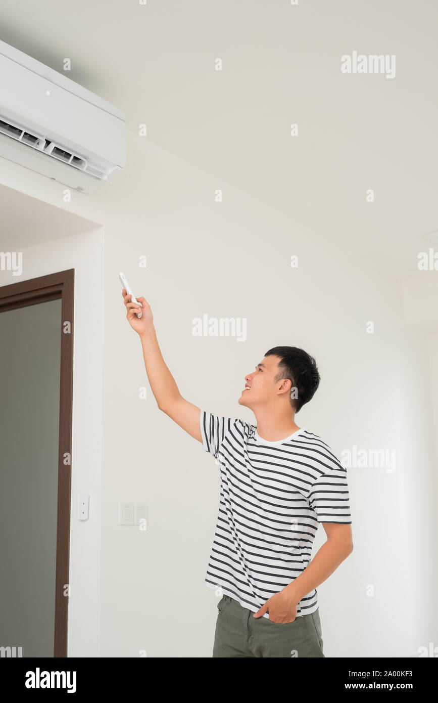 Air conditioner inside unit with man operating remote controller. / Air ...