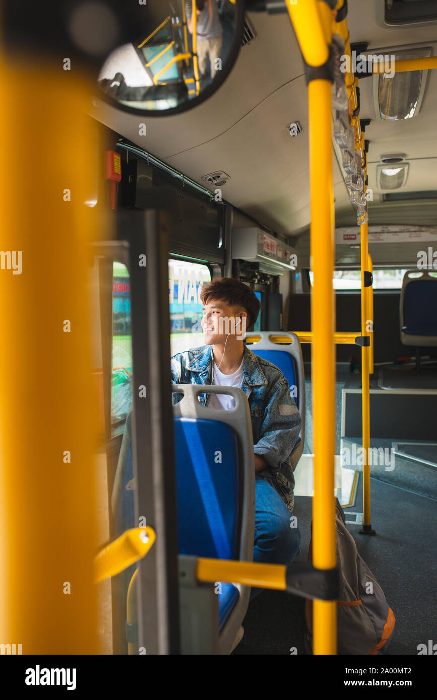Asian young man taking bus to work looking through window Stock Photo ...