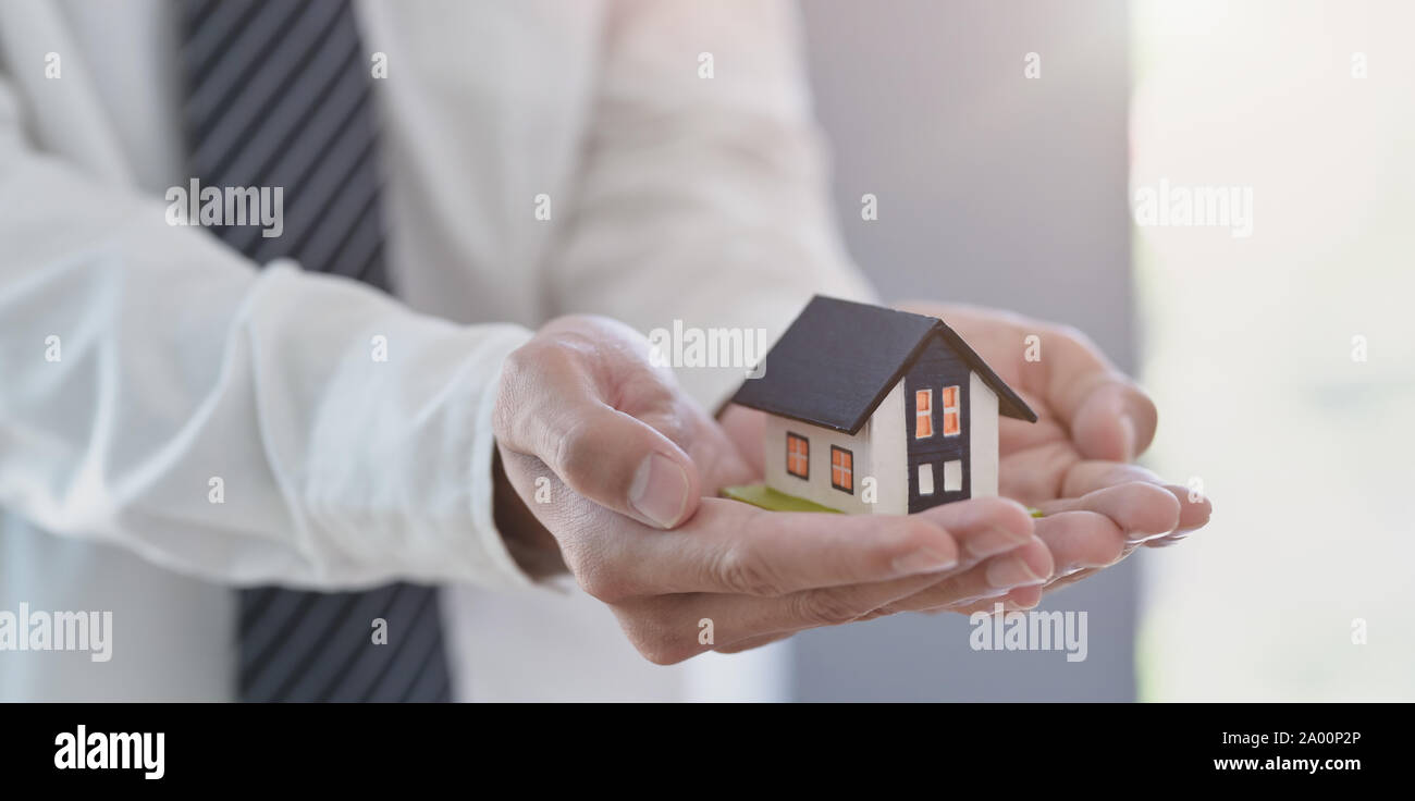 Property insurance concept : insurance agent holding a house model in ...