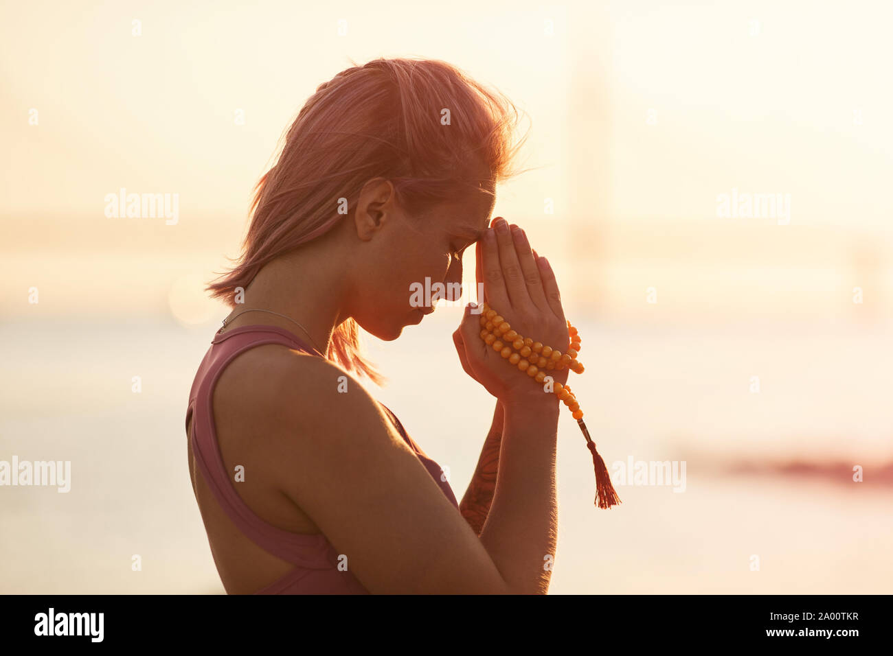 Side view of young healthy woman meditating with her eyes closed during ...