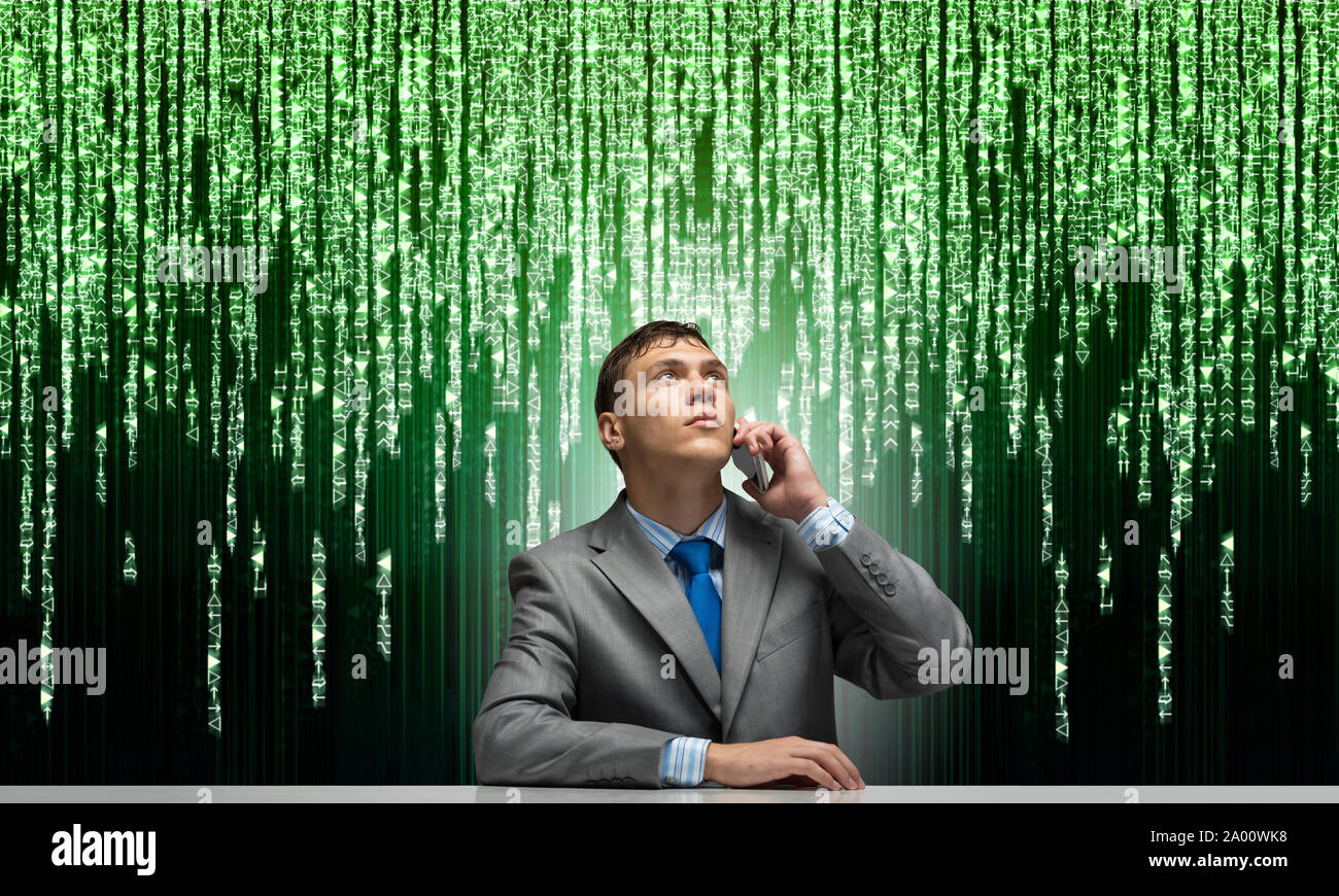 Young man talking on phone and looking upward. Businessman sitting at ...