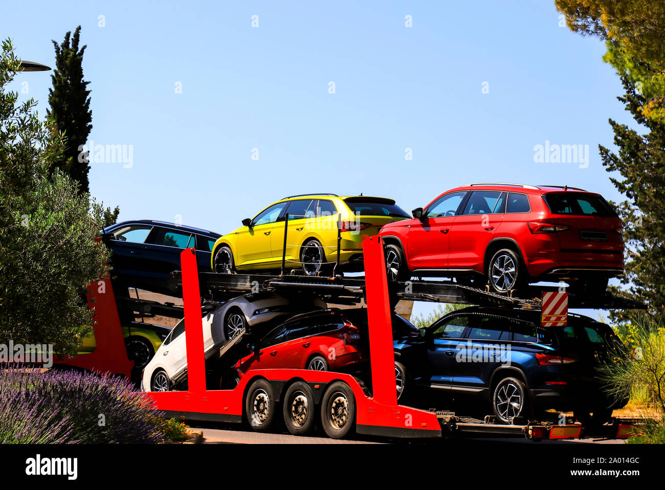 An auto transporter carries new cars of blue, red and yellow colors ...