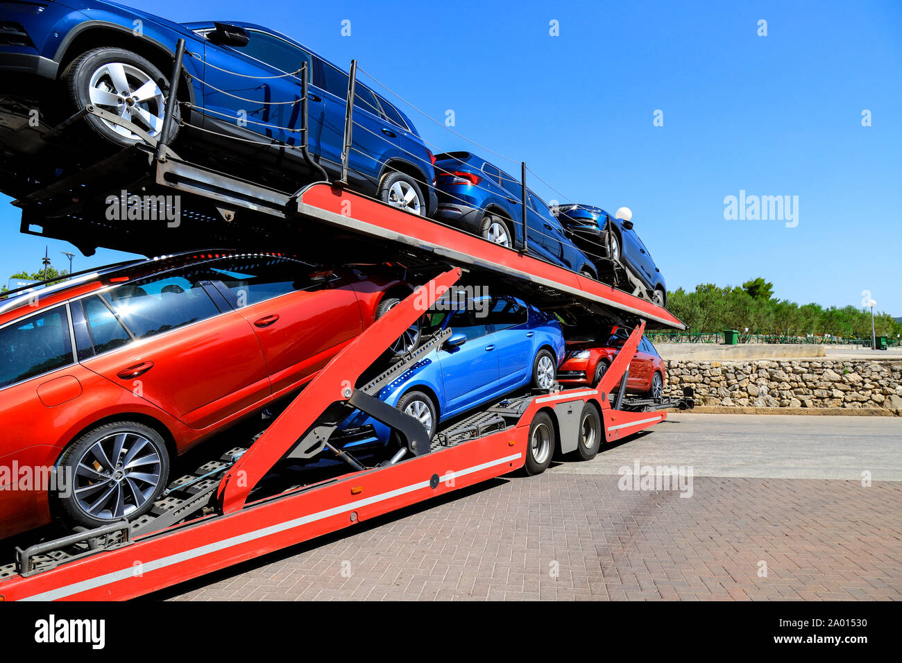 Auto transporter carries new cars of blue, red colors from the factory ...