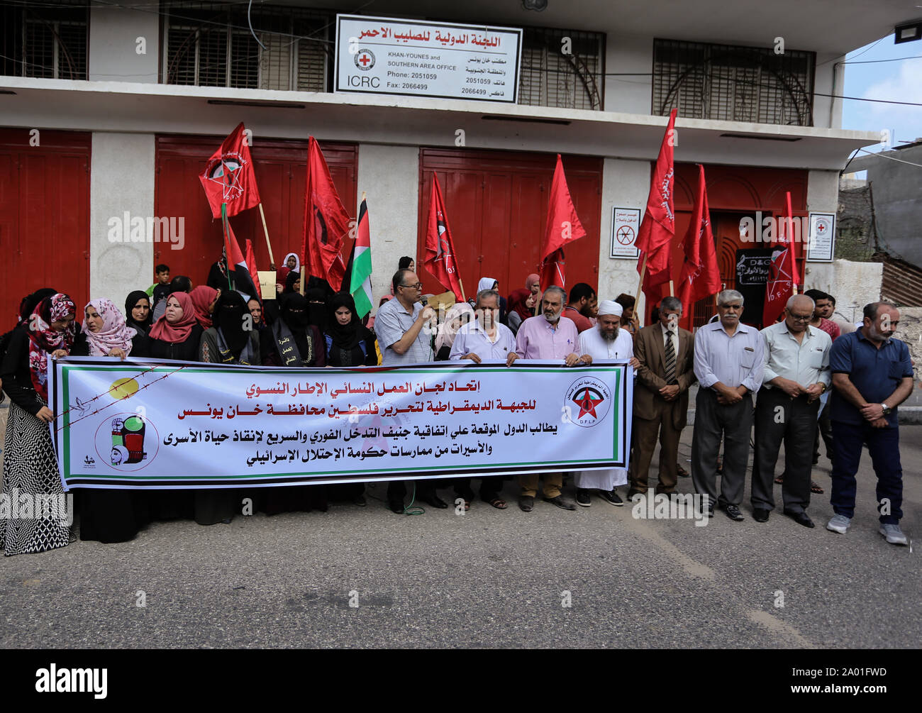 Palestinians hold a banner and flags in front of the Red Cross ...