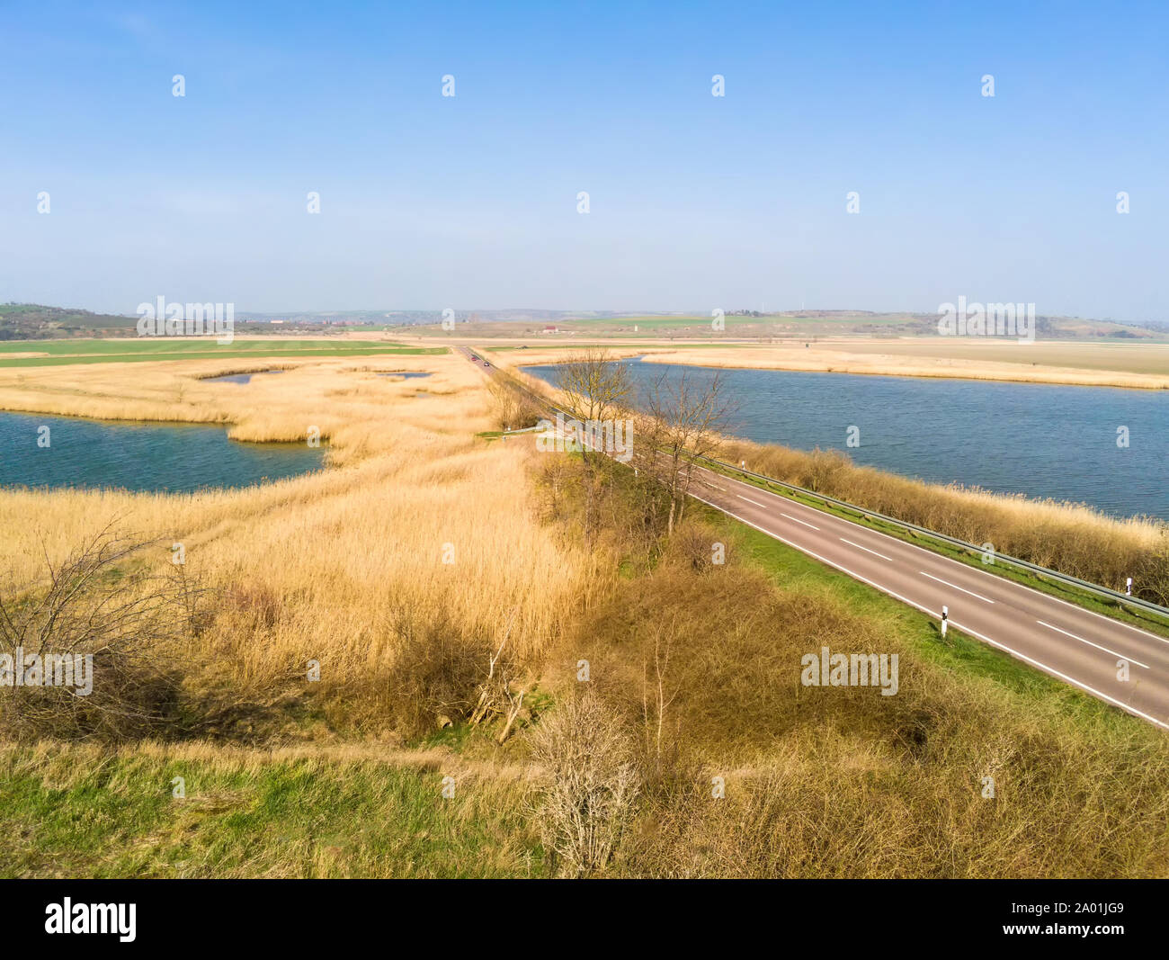 Road leads into the distance between two lakes Stock Photo - Alamy