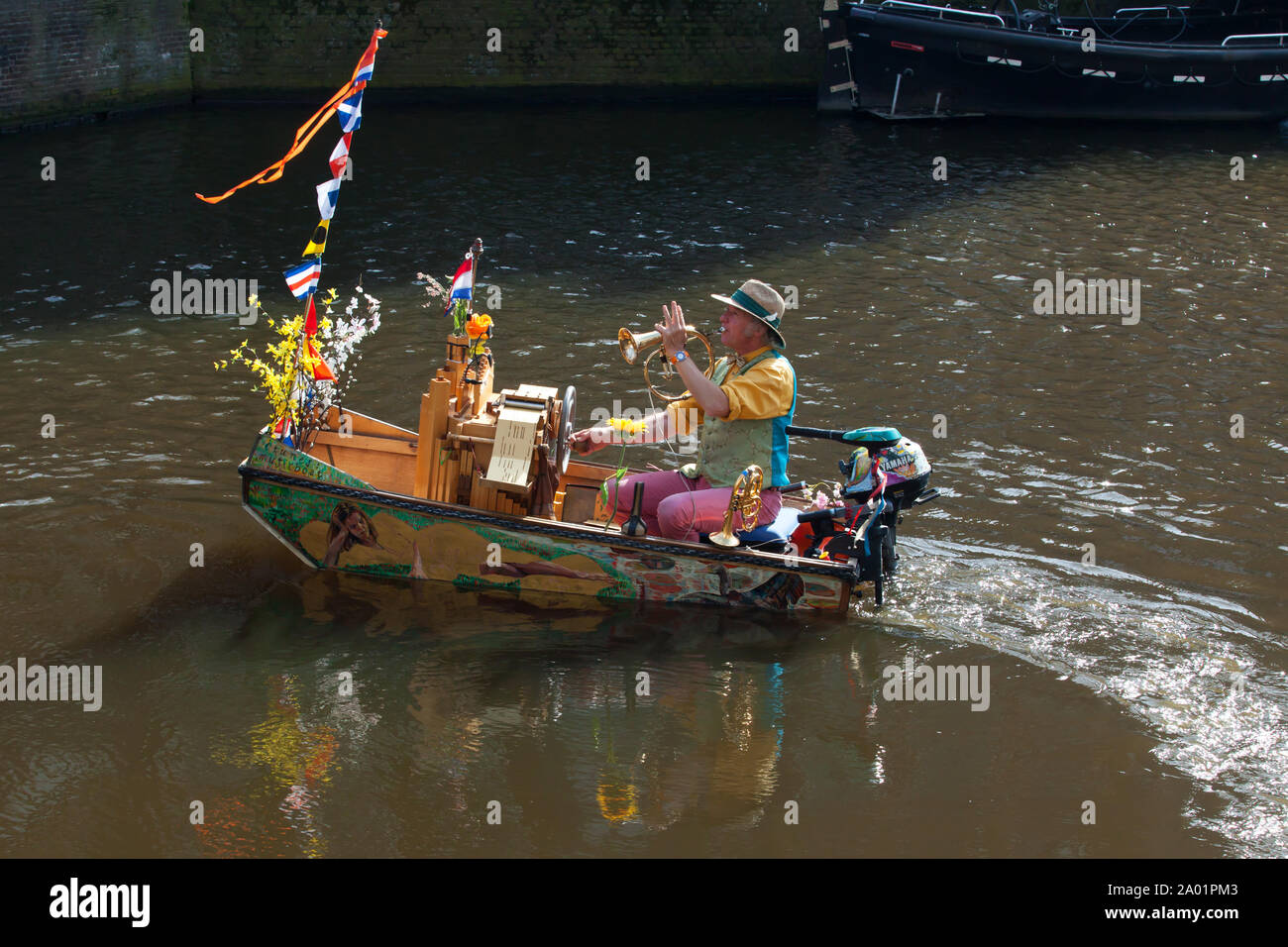 AMSTERDAM - A musician in a boat is playing his organ and trumpet and ...