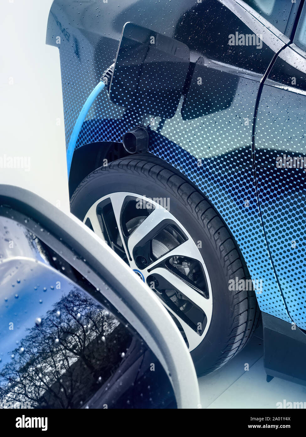 Electric vehicle being plugged in Stock Photo - Alamy