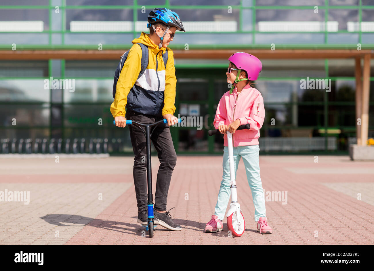 happy school children in helmets riding scooters Stock Photo - Alamy