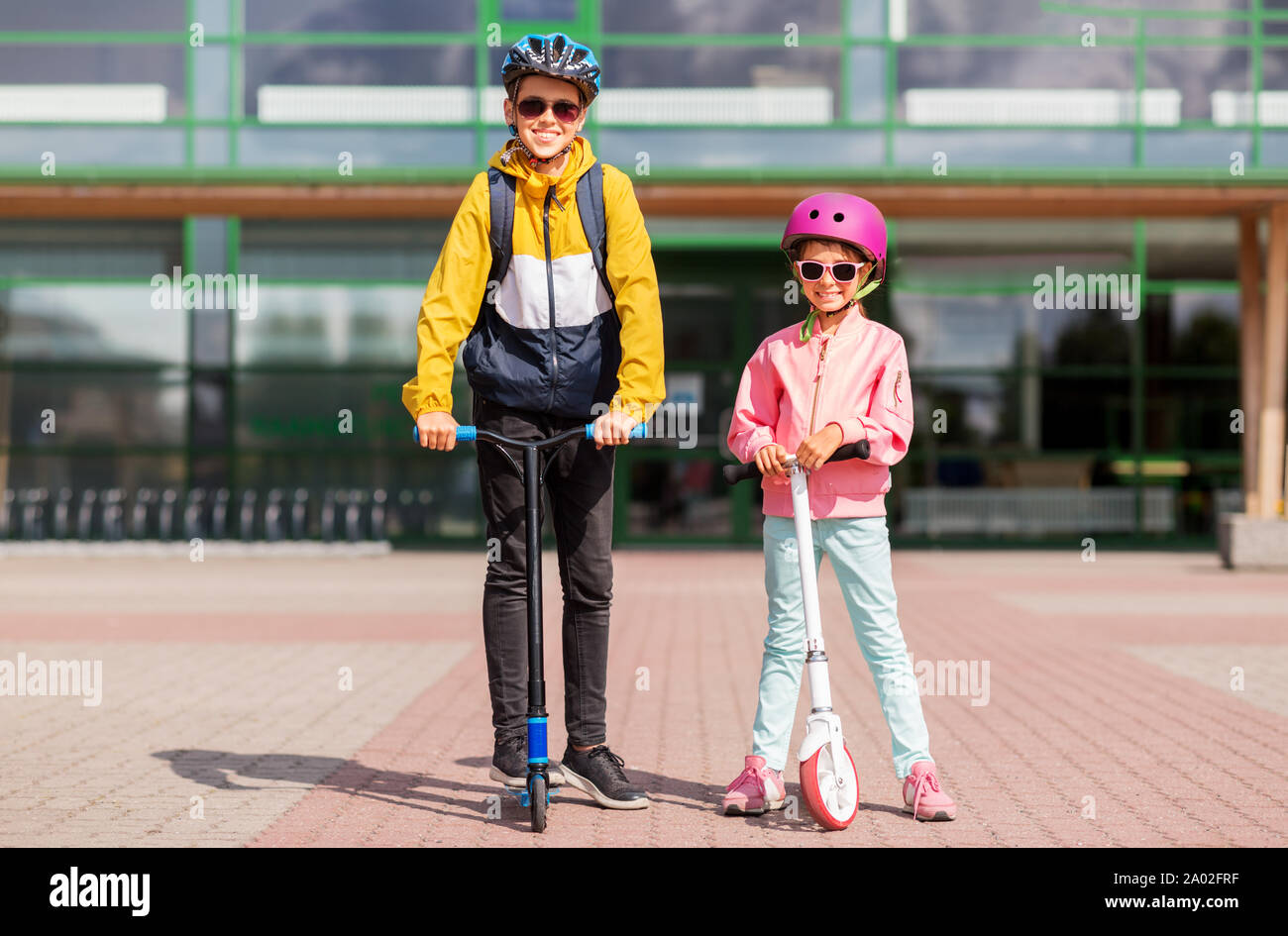 happy school children in helmets riding scooters Stock Photo - Alamy