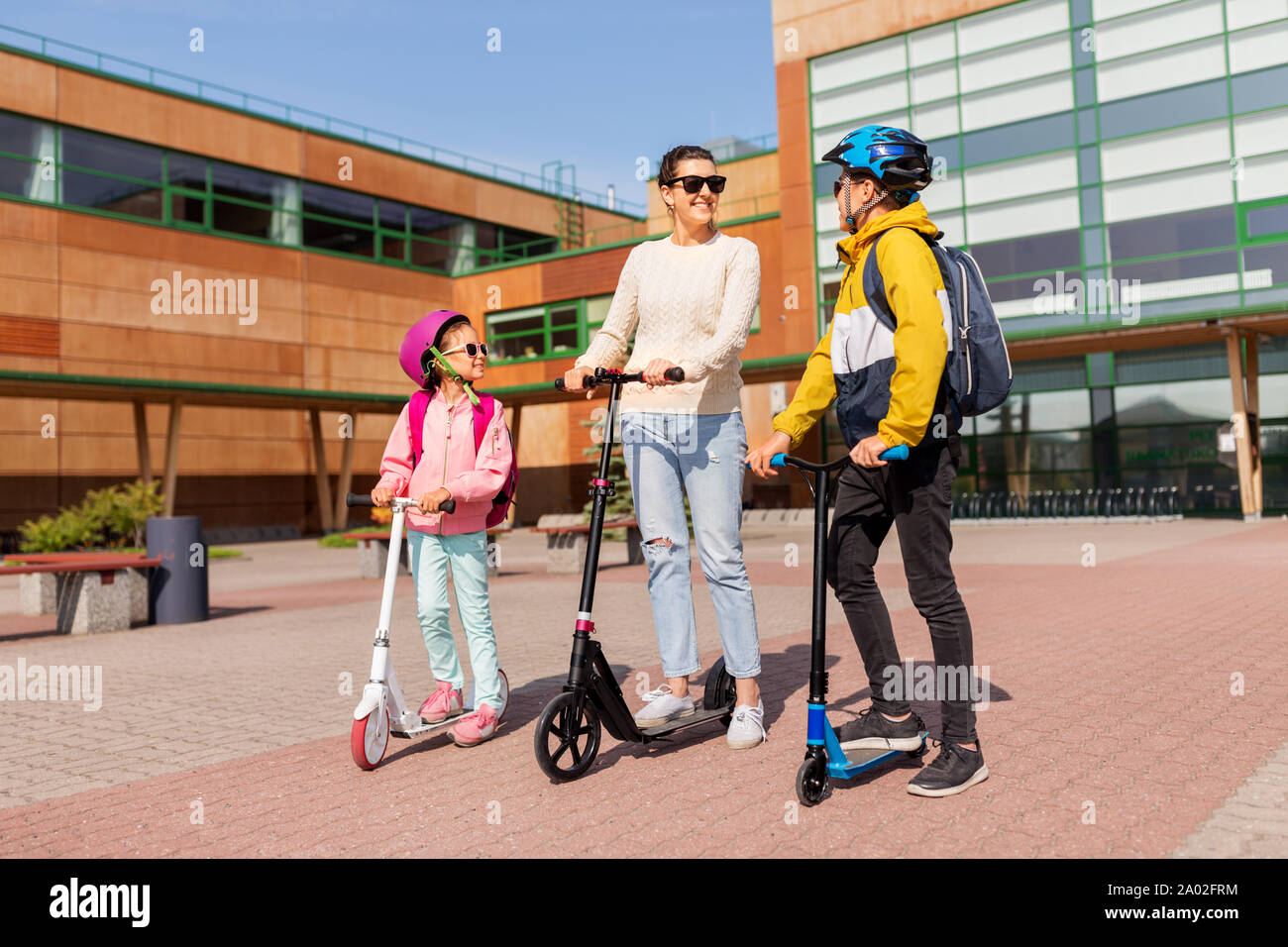 happy school children with mother riding scooters Stock Photo - Alamy