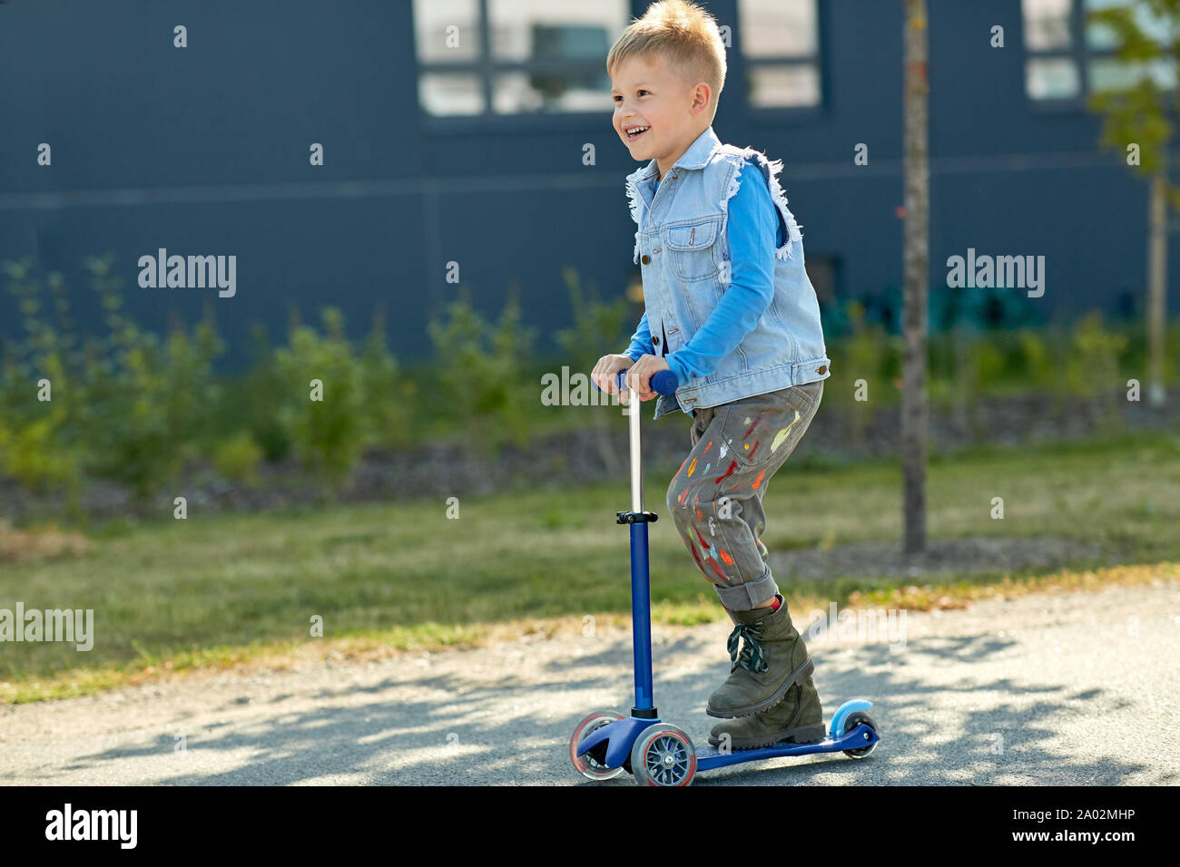 happy little boy riding scooter in city Stock Photo - Alamy