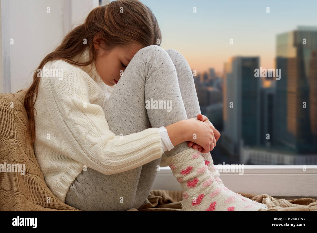 sad girl sitting on sill at home window over city Stock Photo - Alamy