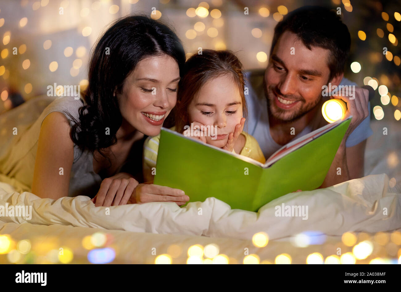 happy family reading book in bed at night at home Stock Photo - Alamy
