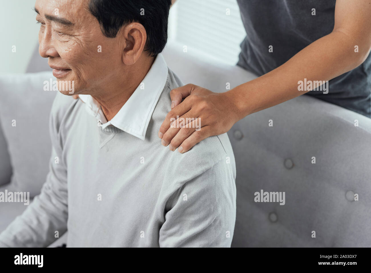Asian old man shoulder pain, sitting on sofa , son massaging father ...