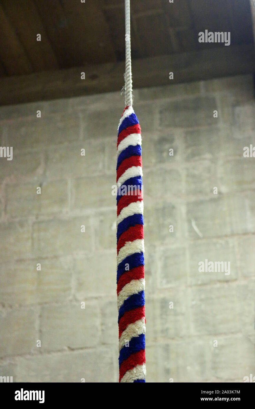 Red, white and blue coloured bell rope hanging down from the bell tower ...