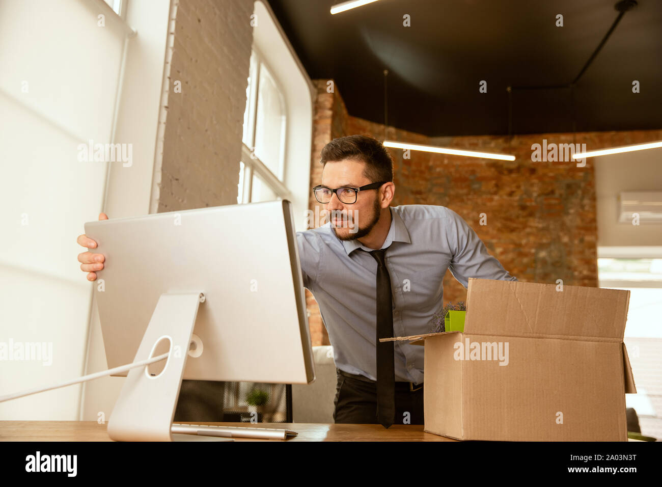 A young businessman moving in the office, getting new work place. Young ...