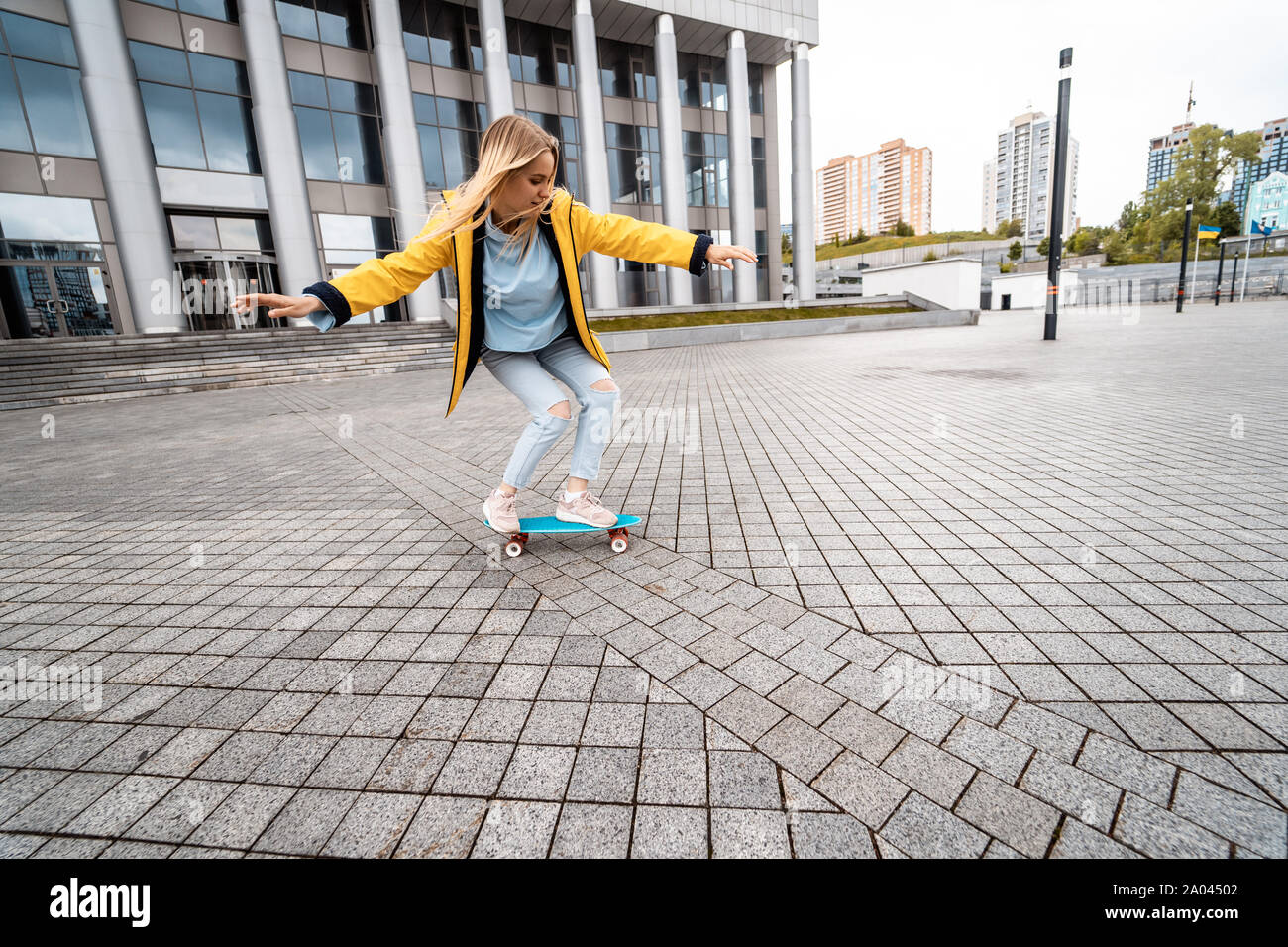 Blond female hipster woman riding on the longboard in the street at ...