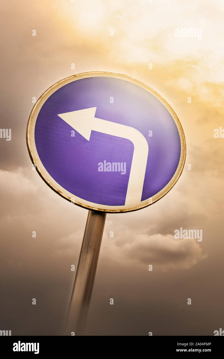 Turn left ahead sign, blue round roadside traffic signage, against the ...