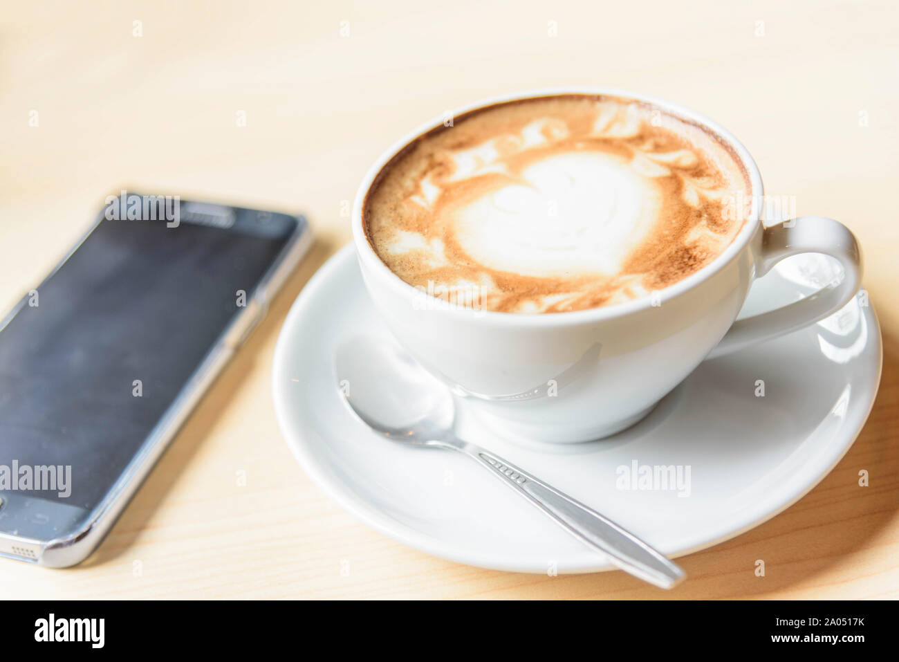 hot coffee on table with smartphone / hot cappuccino with nice pattern ...