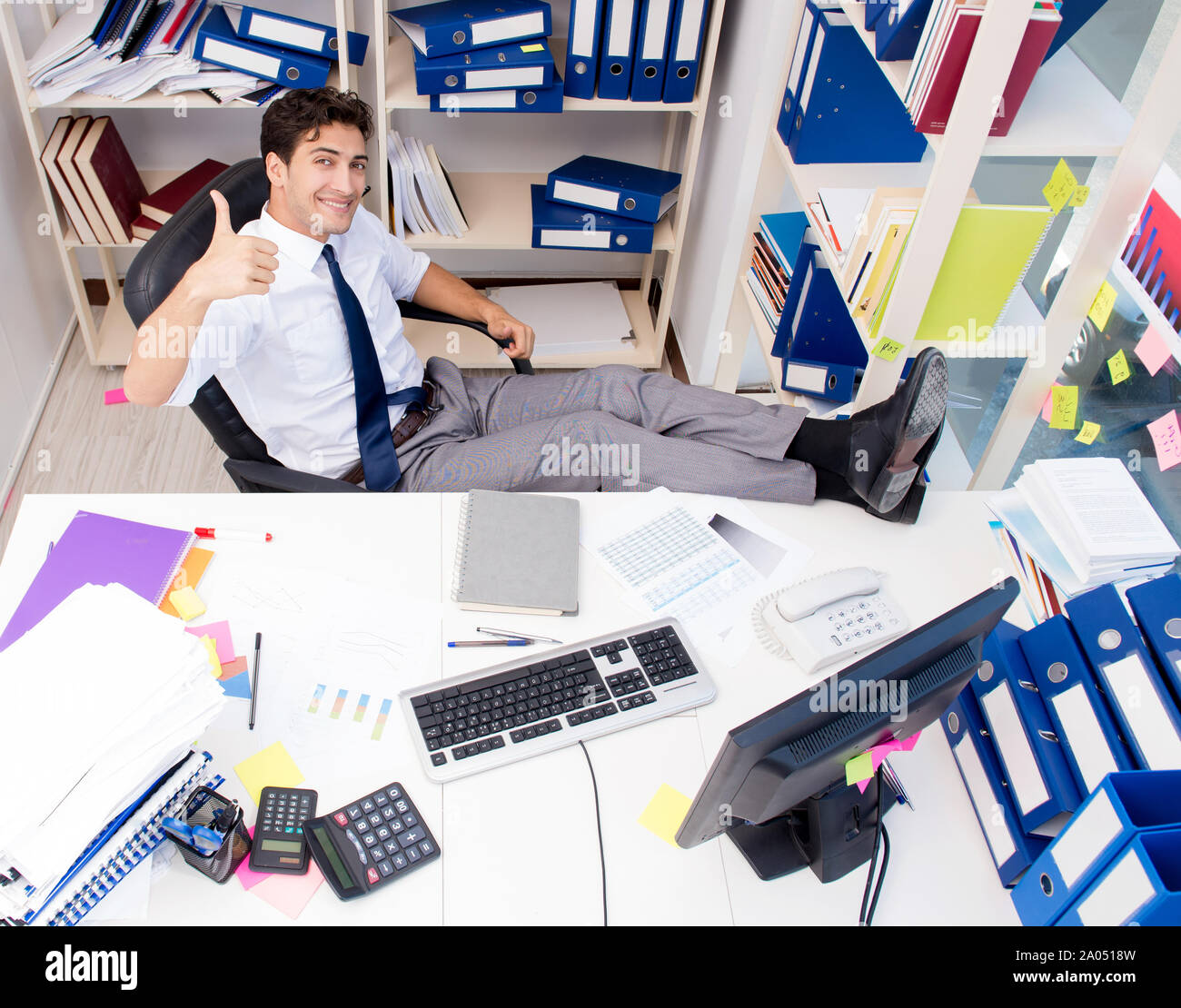 Businessman working in the office with piles of books and papers doing ...