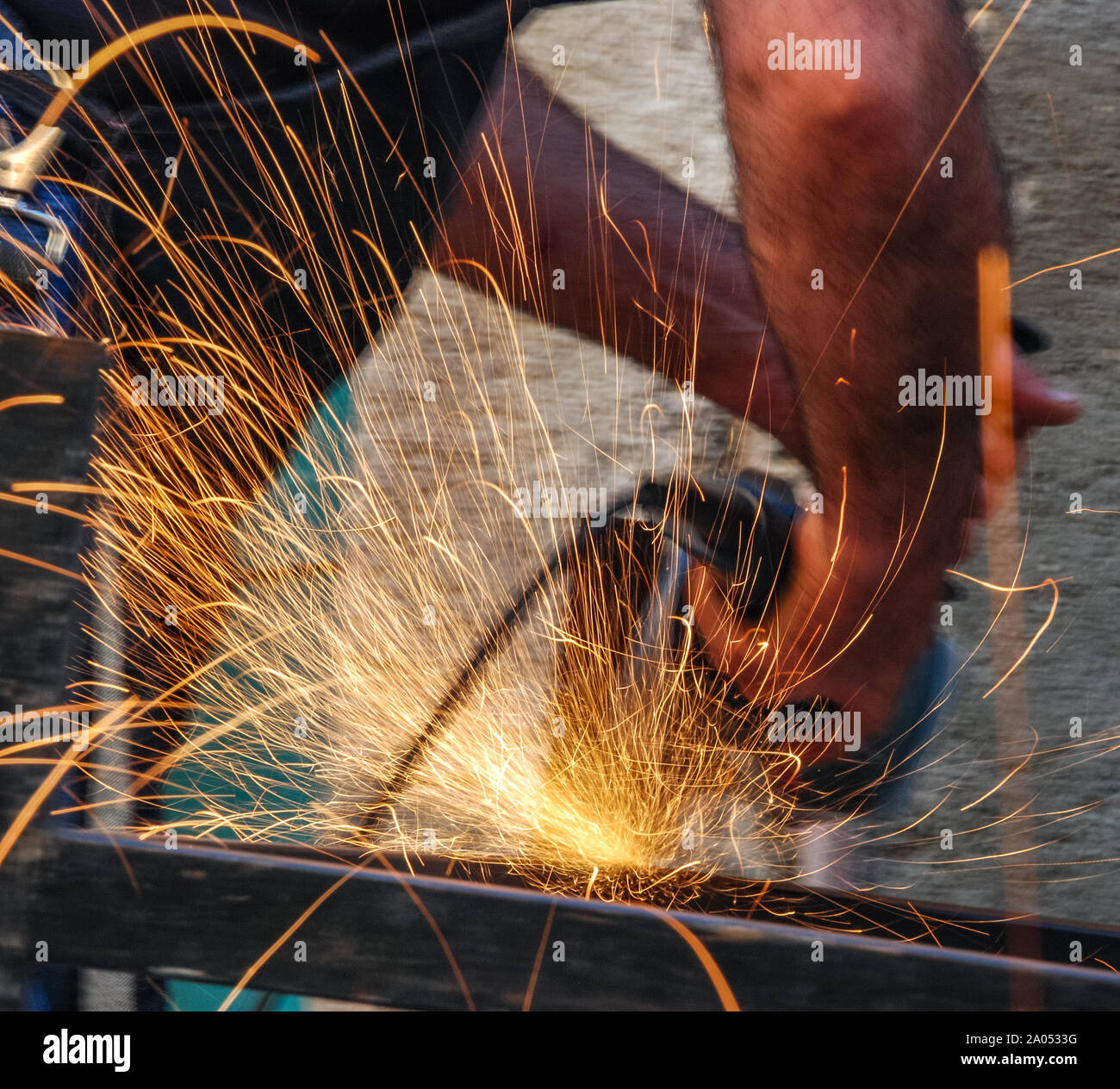 A construction. worker using an angle grinder producing a lot of sparks ...