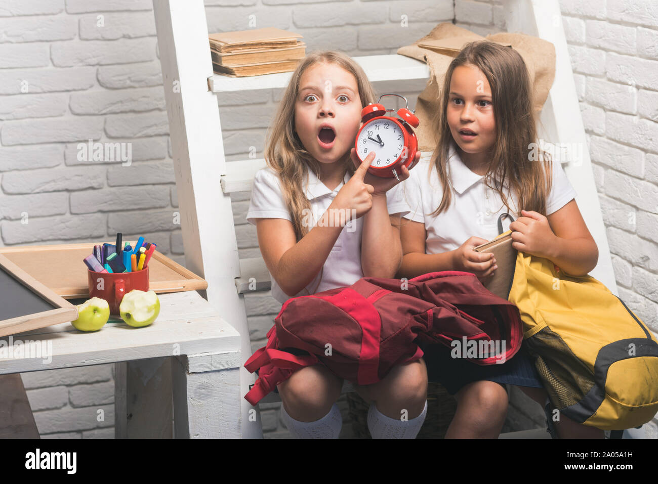 Late. Shoked small girls show time on clock. small kids late to school ...