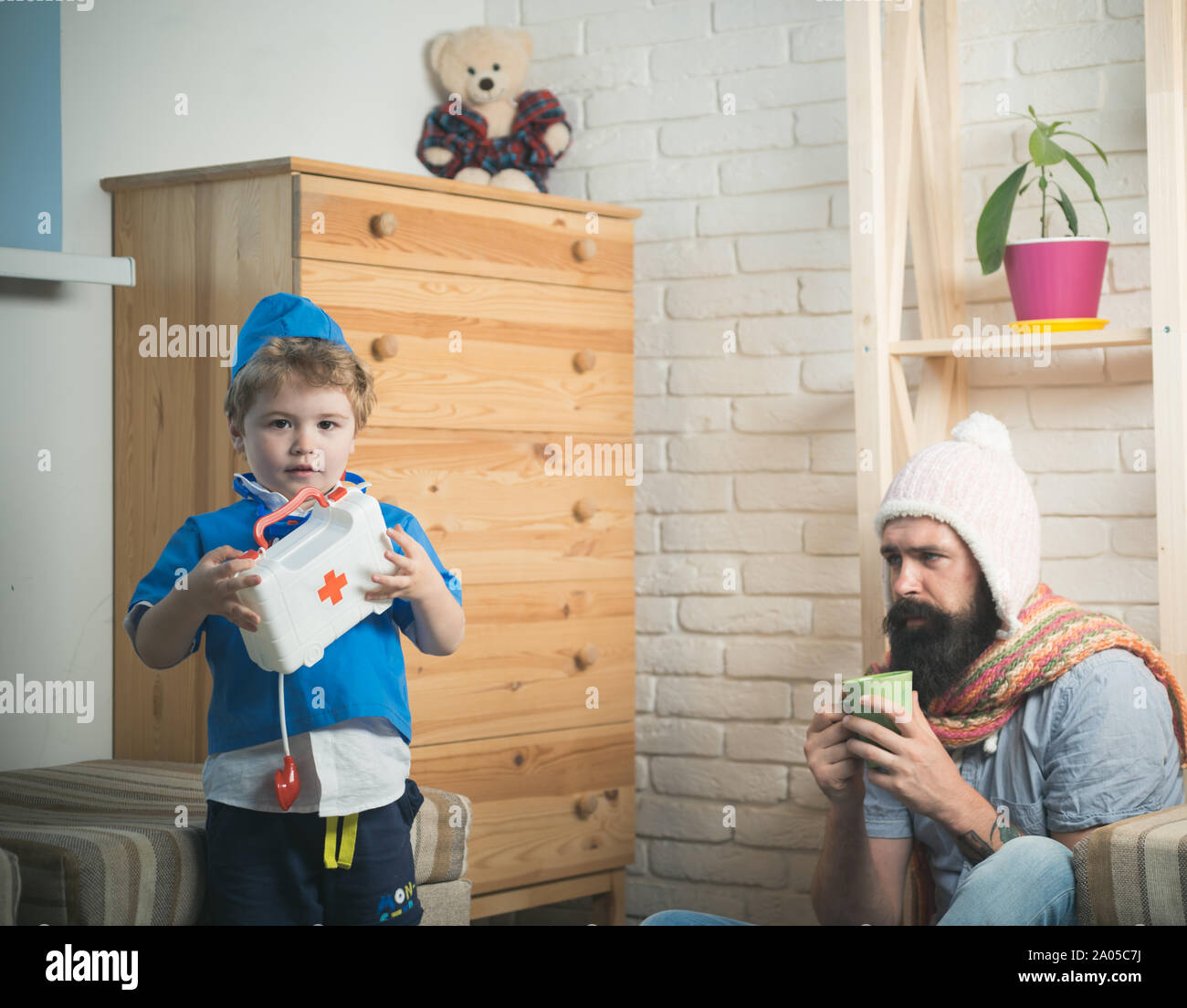 Kid with first aid kit dressed as doctor helping father with severe ...