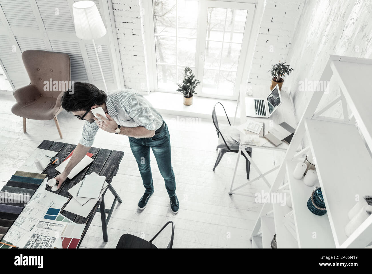 Cheerful young office worker looking at his table Stock Photo - Alamy