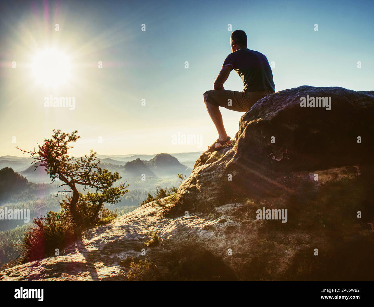 The man standing high on cliff. Hiker climbed up to rocky peak and ...