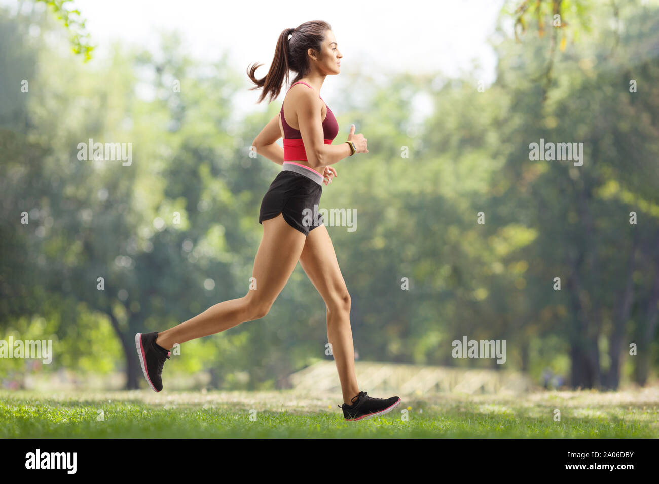 Full length profile shot of a young female athlete jogging outdoors ...