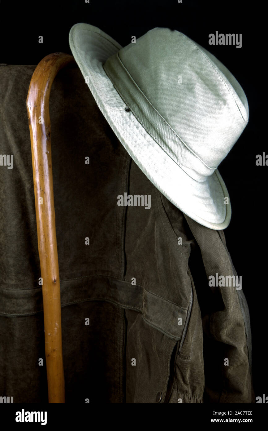 Outdoor coat hat and walking stick isolated on a black background Stock ...