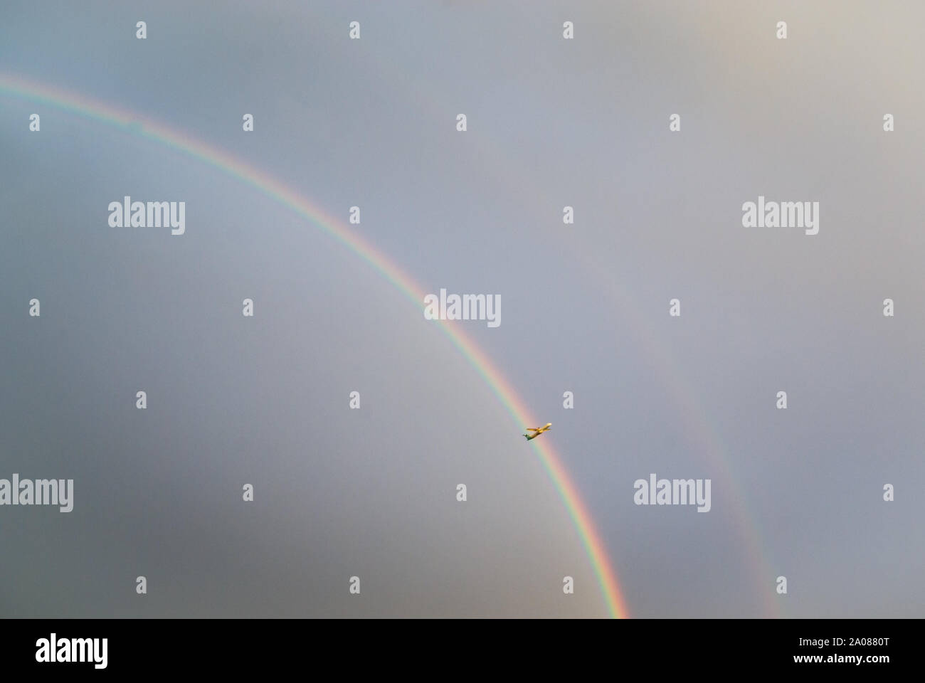jet flying in the sky crossing a rainbow at distance Stock Photo - Alamy
