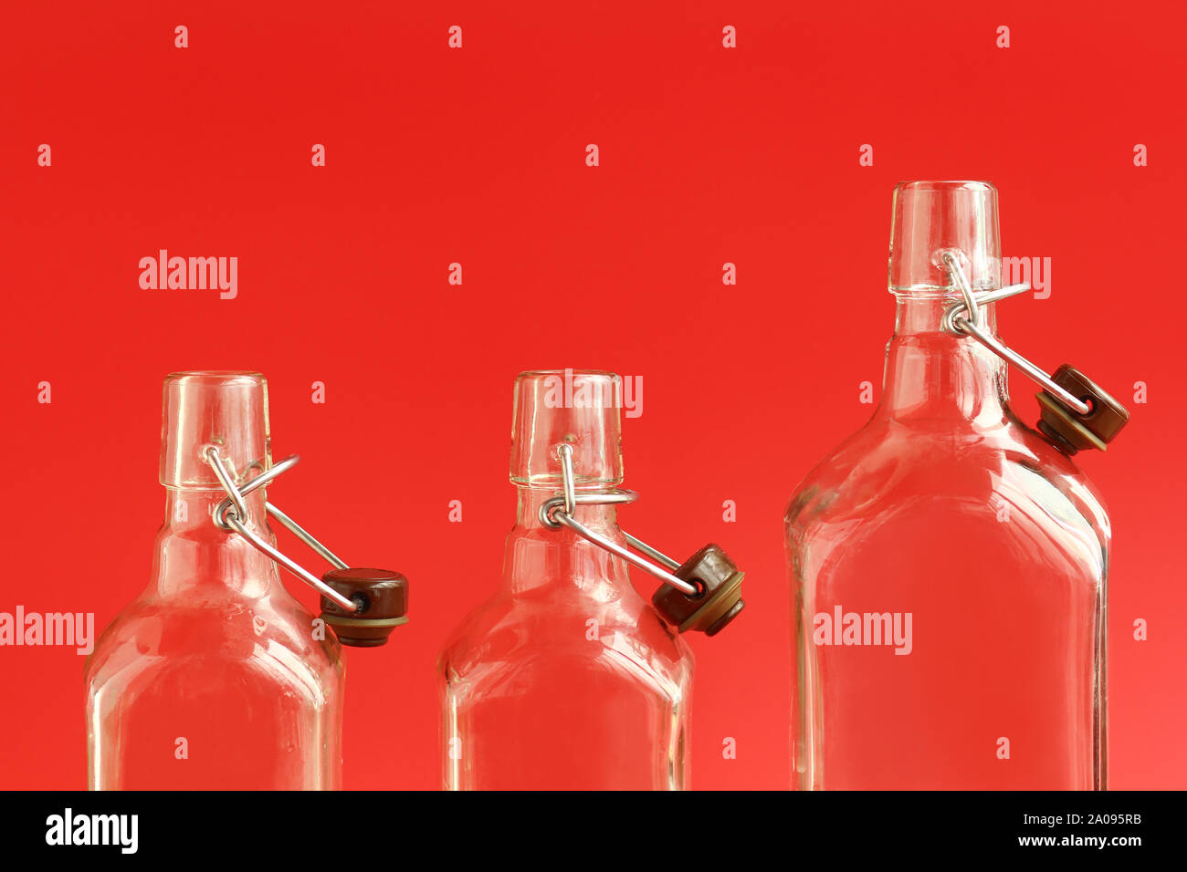 Closeup of three glass empty open bottles over red background Stock ...
