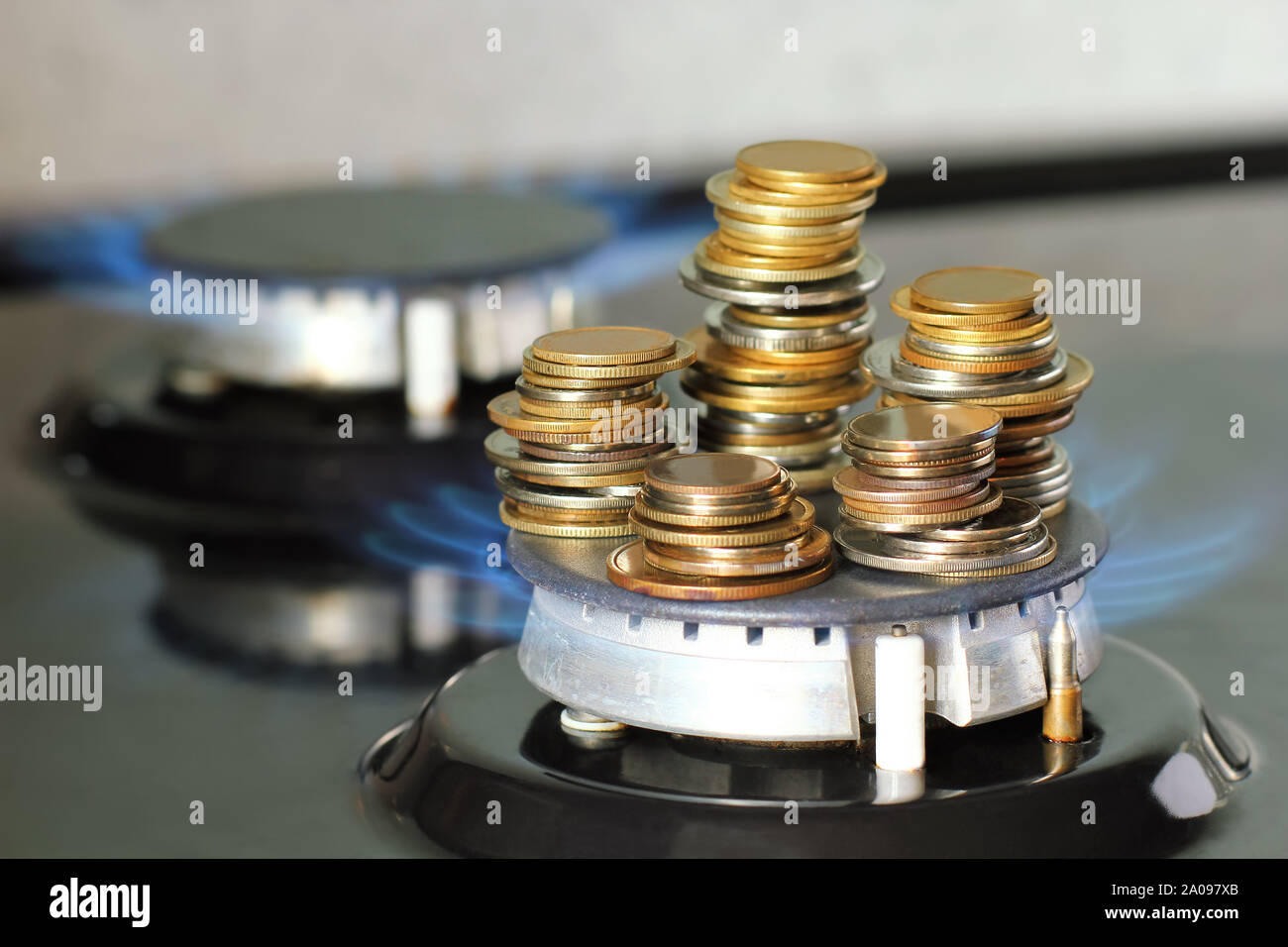 Stack of coins on kitchen stove, blue flame of natural gas burner ...
