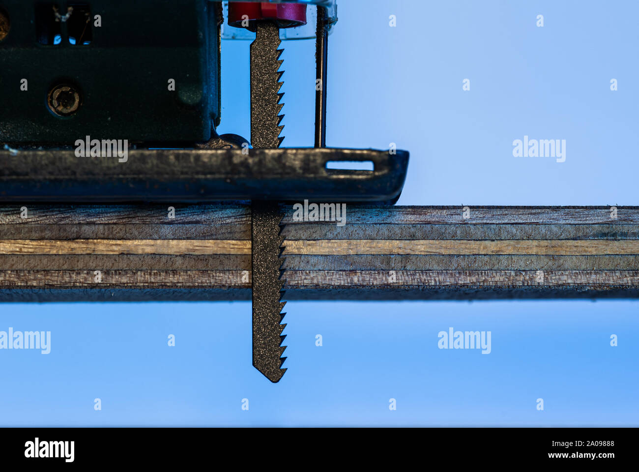 Side view of jigsaw blade and jigsaw on a piece of laminated wood with ...
