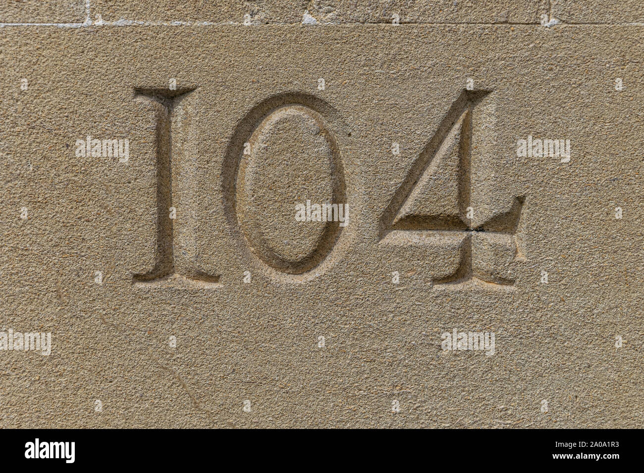 Number 104 carved in a limestone ashlar wall Stock Photo - Alamy