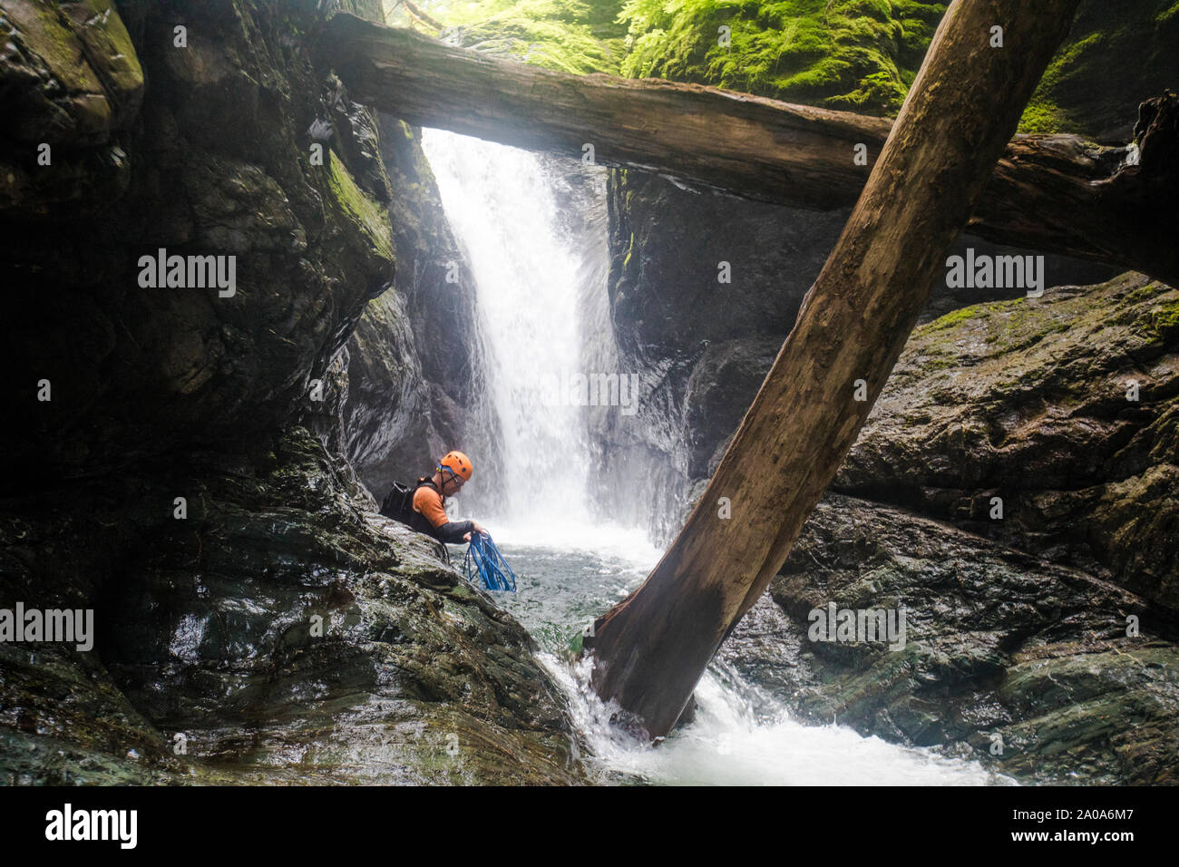 Man coils rope after rappelling down a waterfall Stock Photo - Alamy