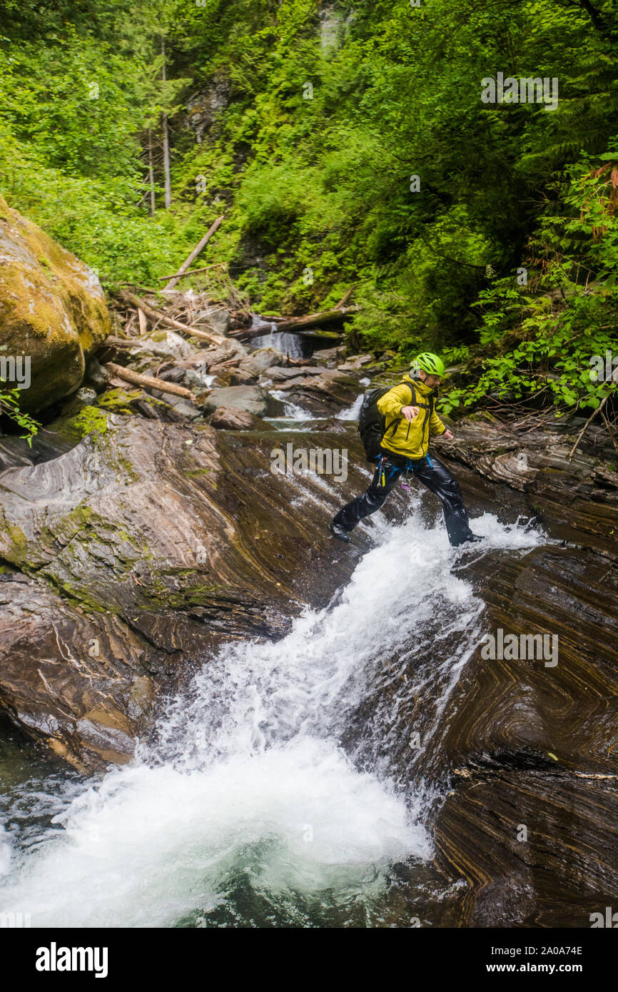 Hiker steps over small waterfall in the lower section of Frost Creek ...