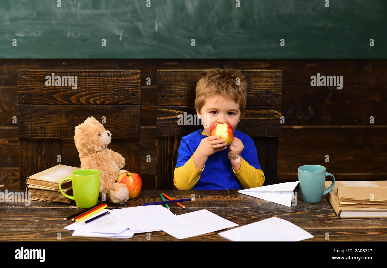 School break. Hungry kid eating apple in classroom. Small boy playing ...