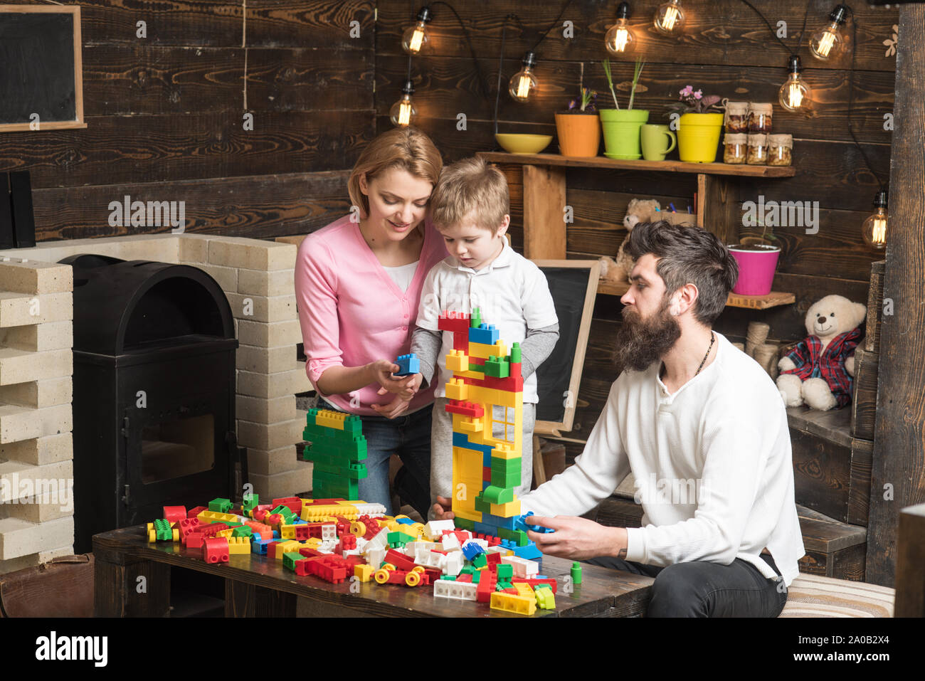 Mom, dad and kid sitting around table with colorful construction bricks ...