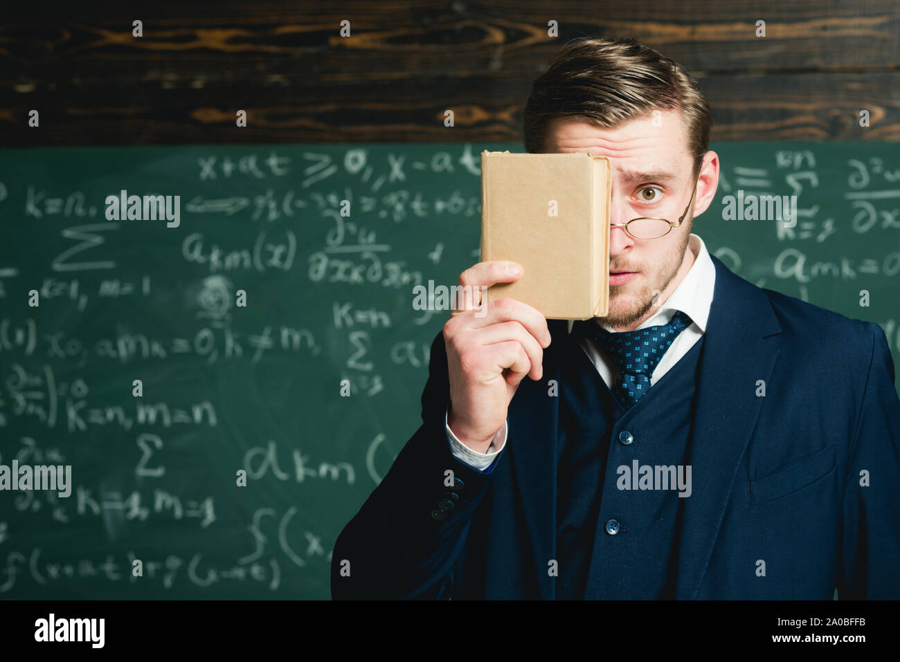 Surprised guy hiding his face behind book cover. Portrait of young ...