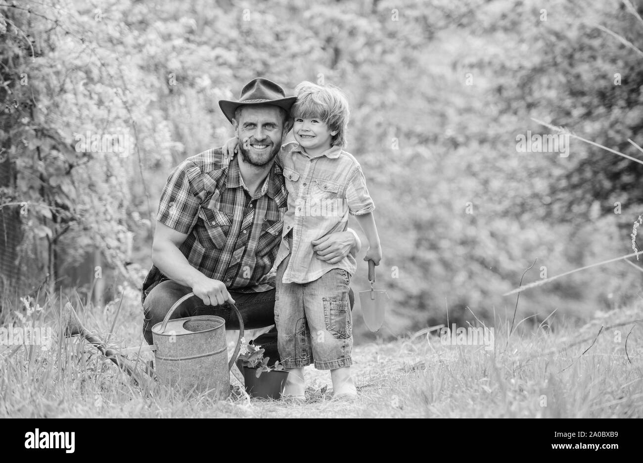 Boy and father in nature with watering can. Spring garden. Dad teaching ...