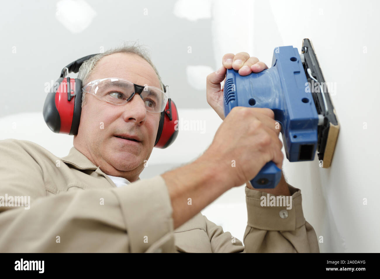 senior man using sander on a plasterboard wall Stock Photo - Alamy