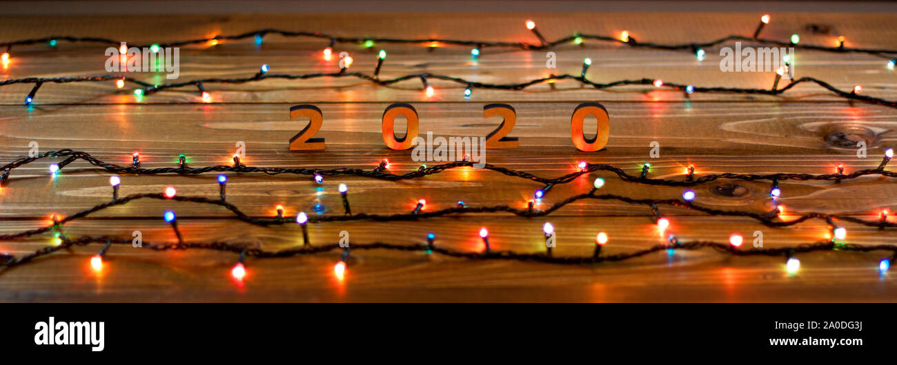 Wooden numbers forming the number 2020 and Christmas lights on a wooden ...