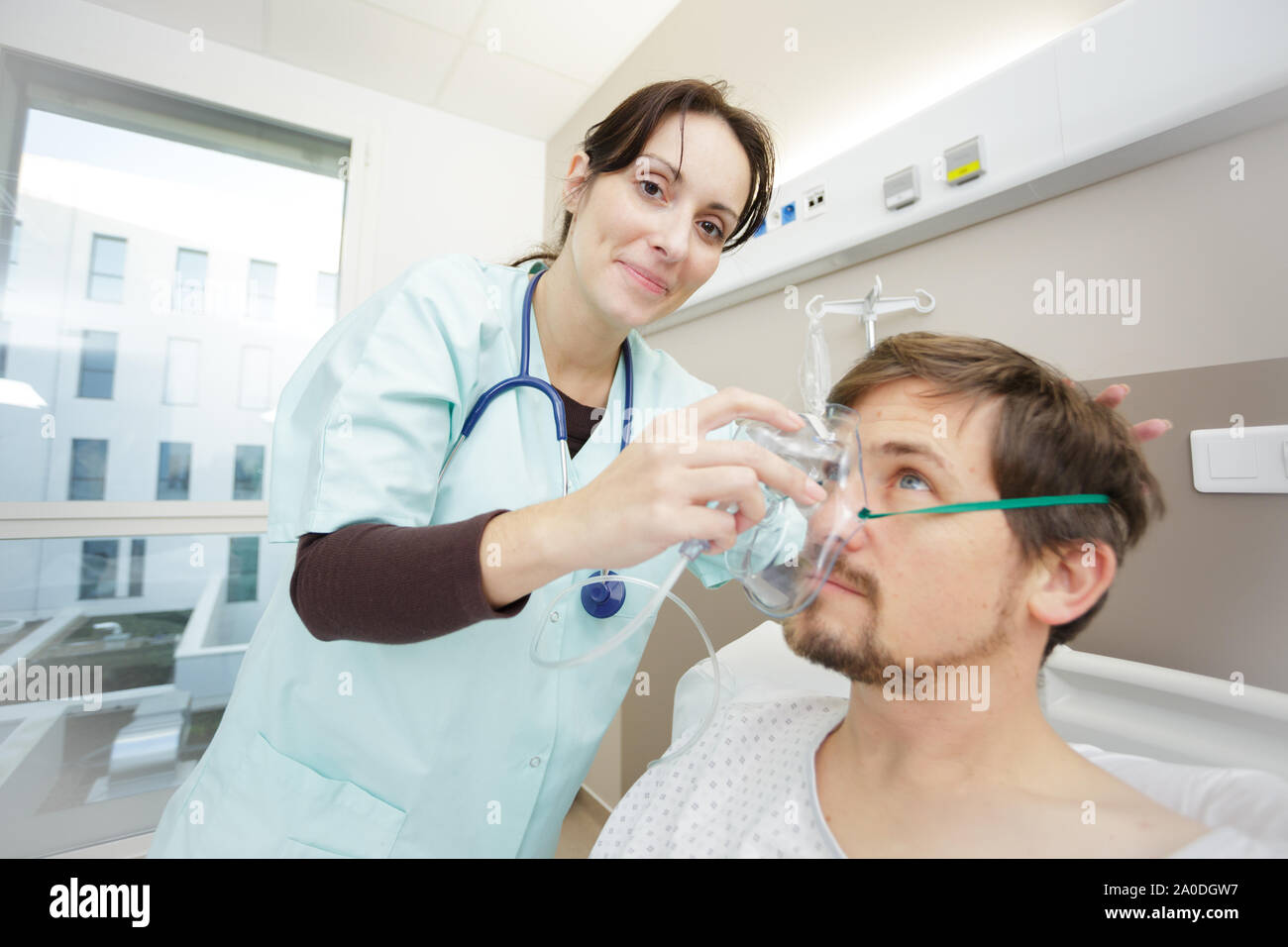 female doctor holding oxygen mask over male patients face Stock Photo ...
