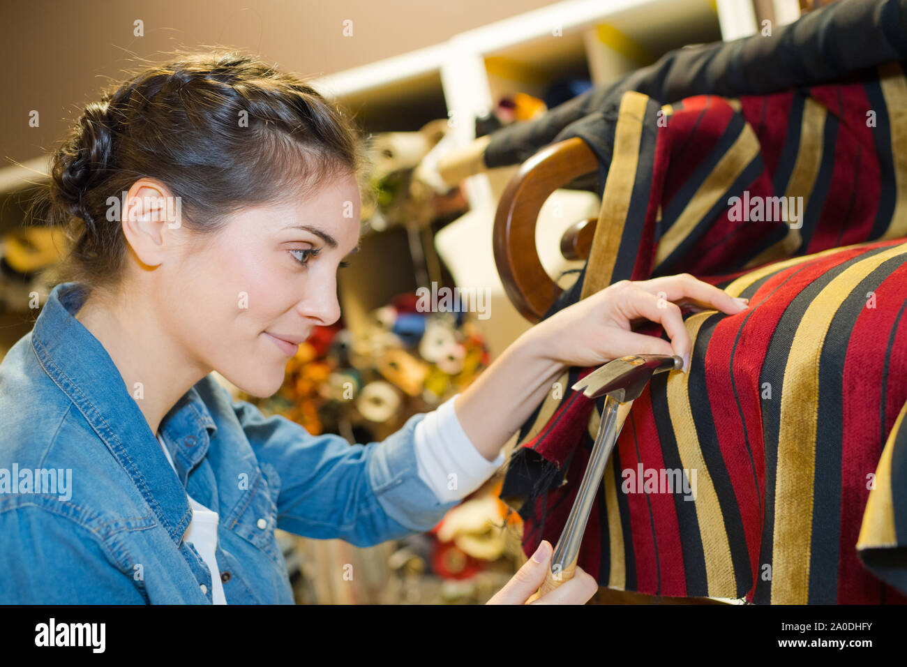 female reupholsterer tacking material on to chair Stock Photo - Alamy