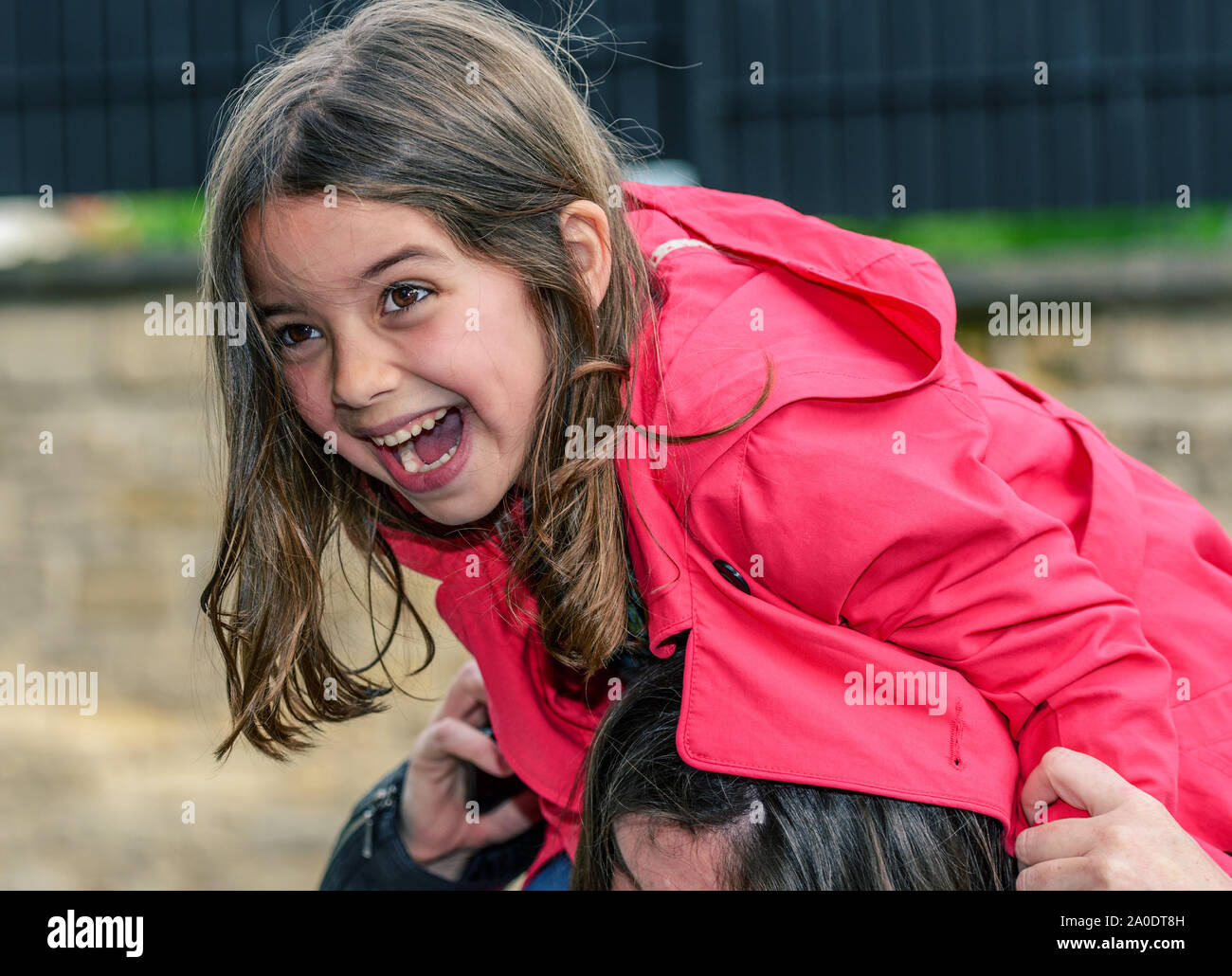 pretty laughing child perched on the shoulder of her mother Stock Photo ...