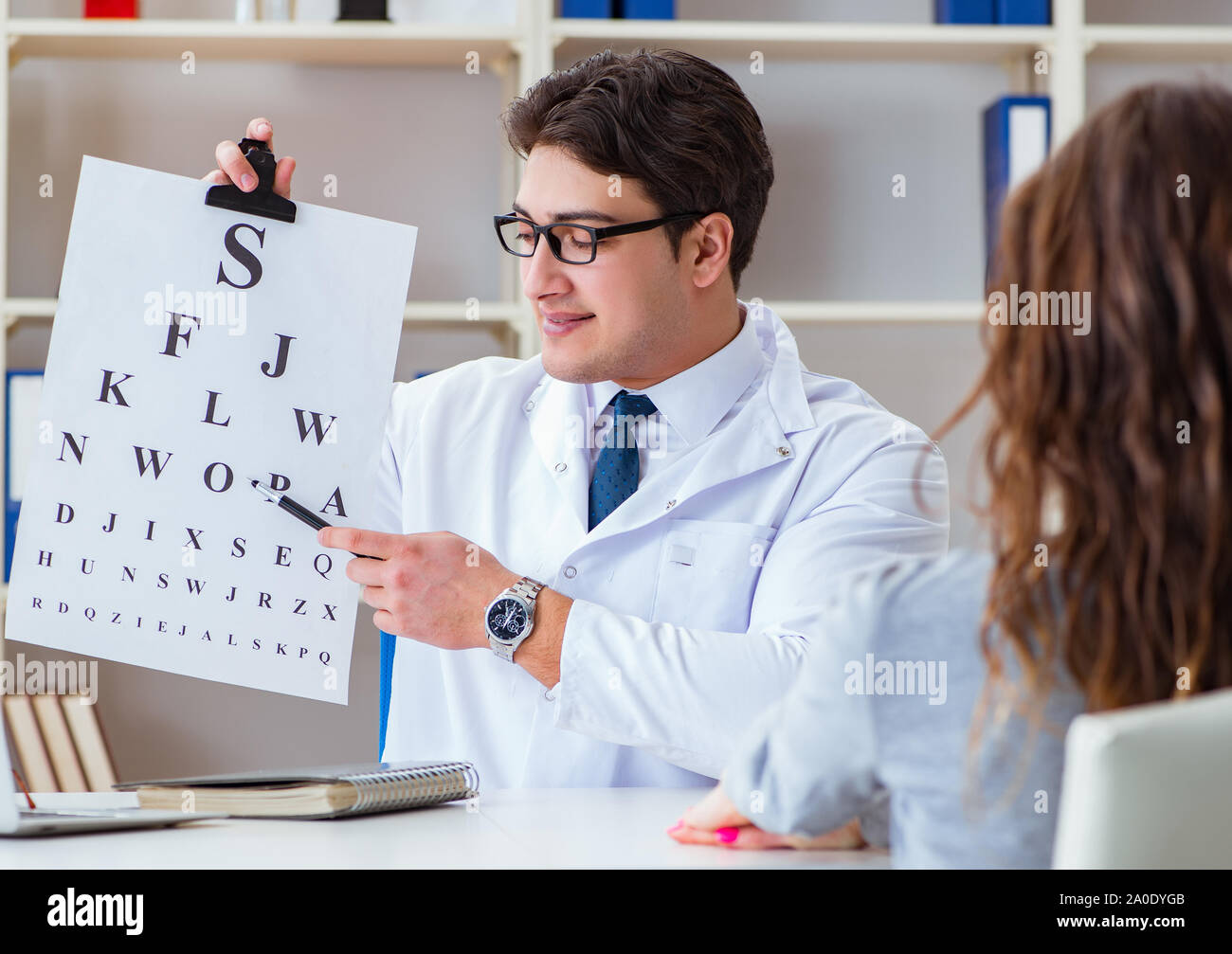 The doctor optician with letter chart conducting an eye test check ...