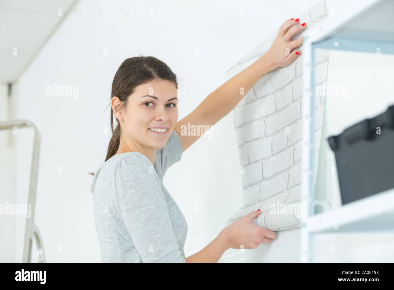 girl going to cover the wall with wall paper Stock Photo - Alamy