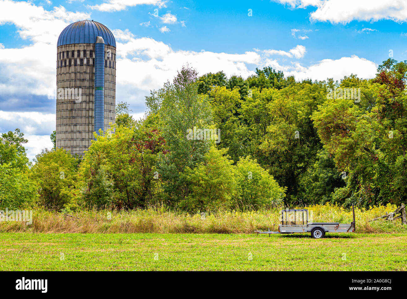 A stave silo for storing grain is seen emerging from surrounding trees ...